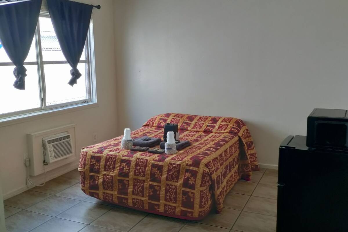 Quarto com cama, aquecedor, janela com cortinas e luminária no teto.