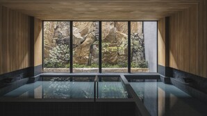 Um spa moderno com uma janela ampla que oferece vista para terreno rochoso e vegetação.