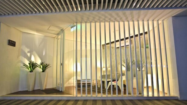 Um interior moderno com divisória de vidro, escada e plantas em vasos.