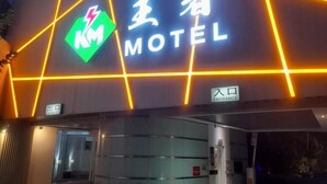 Um motel com um letreiro de neon e uma entrada visível.
