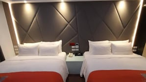 Quarto de hotel com duas camas, uma cabeceira moderna e um claraboia.