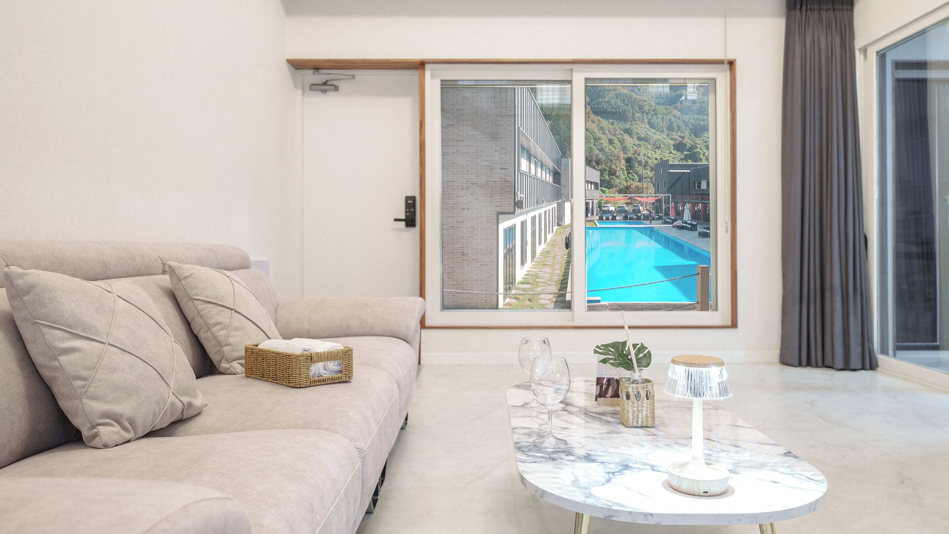 Uma sala de estar moderna com sofá, mesa de centro e uma grande janela com vista para uma piscina.