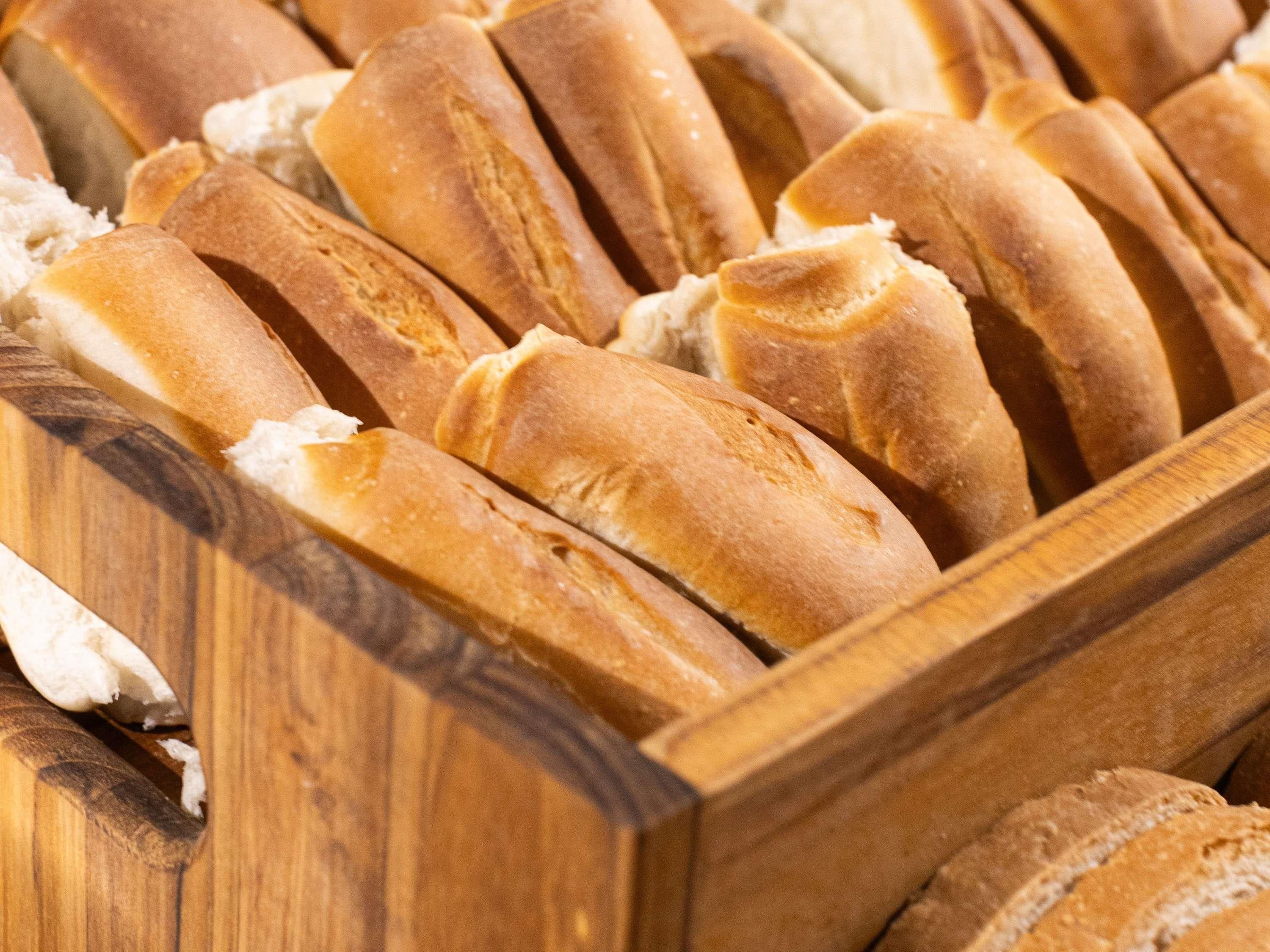 Uma caixa de pão de madeira com vários pães.