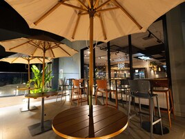 Restaurante com área externa, incluindo mesas e cadeiras redondas sob grandes guarda-sóis.