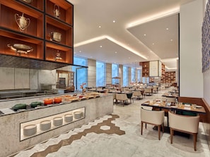 Um restaurante moderno com ilha central, mesas de jantar e diversos pratos em exposição.