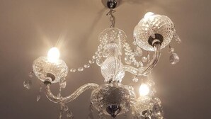 Um candelabro com vários braços de cristal e lâmpadas.