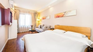 Quarto de hotel com uma cama grande, um sofá, uma escrivaninha e uma televisão.