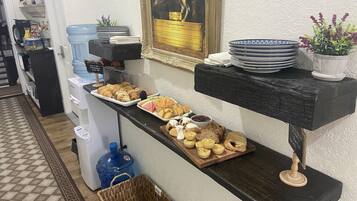 Buffet de café da manhã com diversos pães, frutas e patês em uma bancada preta.