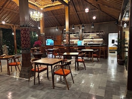A restaurant with wooden tables and chairs, a bar area, and decorative columns.
