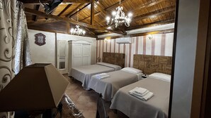 Quarto com duas camas, vigas de madeira no teto, um candelabro e um relógio na parede.