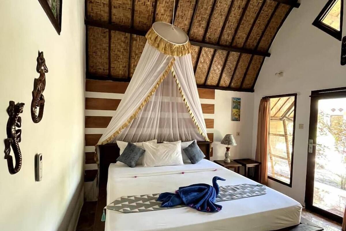 Quarto com cama, dossel, teto de madeira e vista para o exterior.