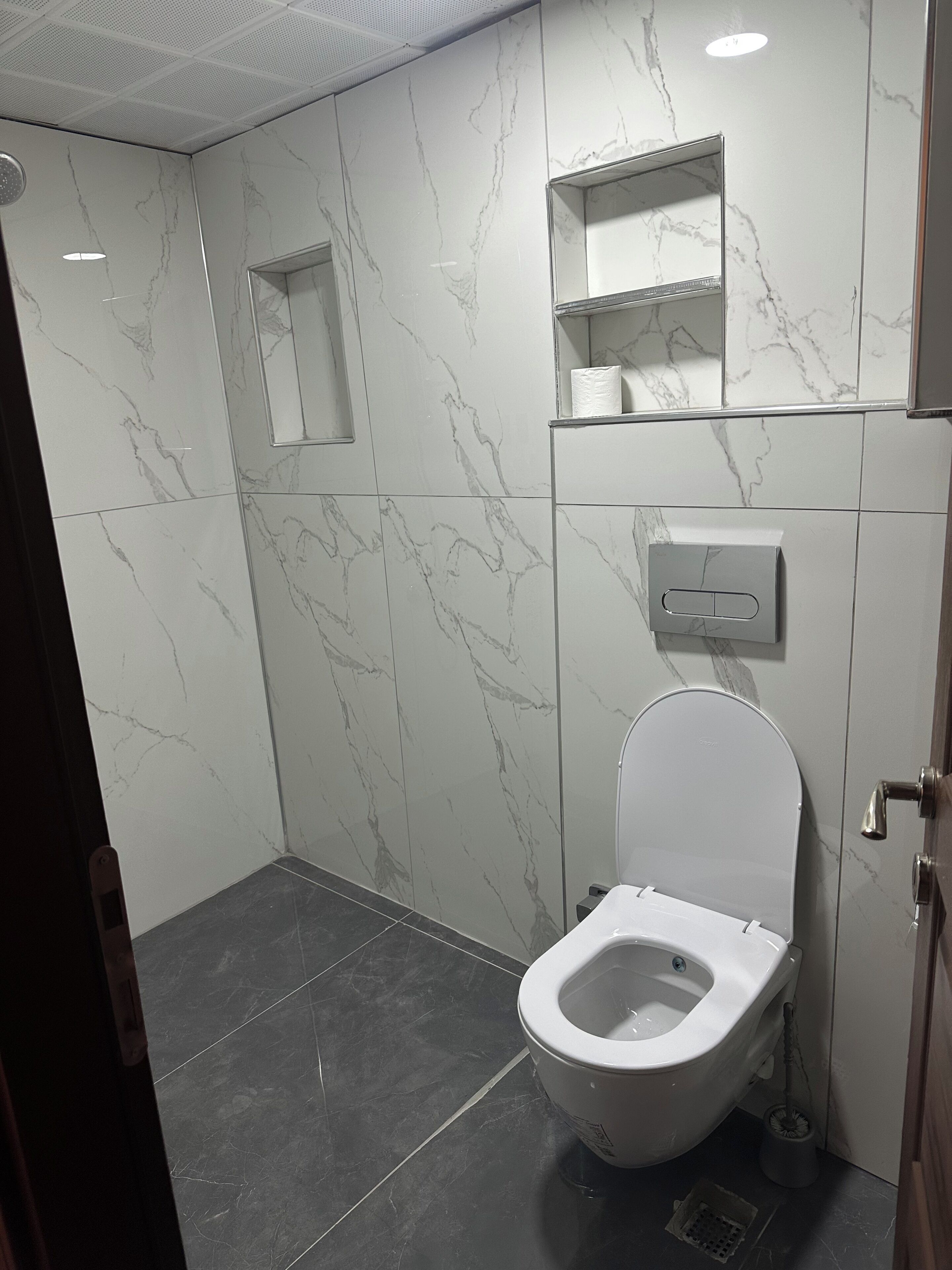 Casa de banho com sanita, secador de mãos e espelho.