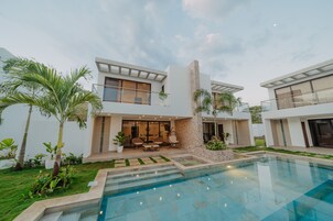 Uma casa moderna de dois andares com piscina, área de estar externa e um jardim bem cuidado.
