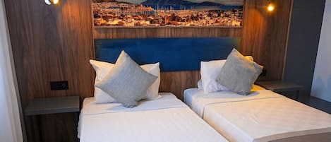 Quarto de hotel com duas camas, vista para a cidade, painéis de madeira e mesas de cabeceira.
