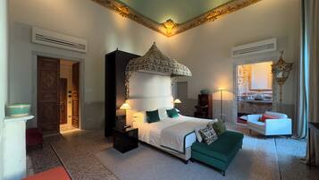 Um quarto espaçoso com uma cama grande, um sofá verde e uma área de estar separada.