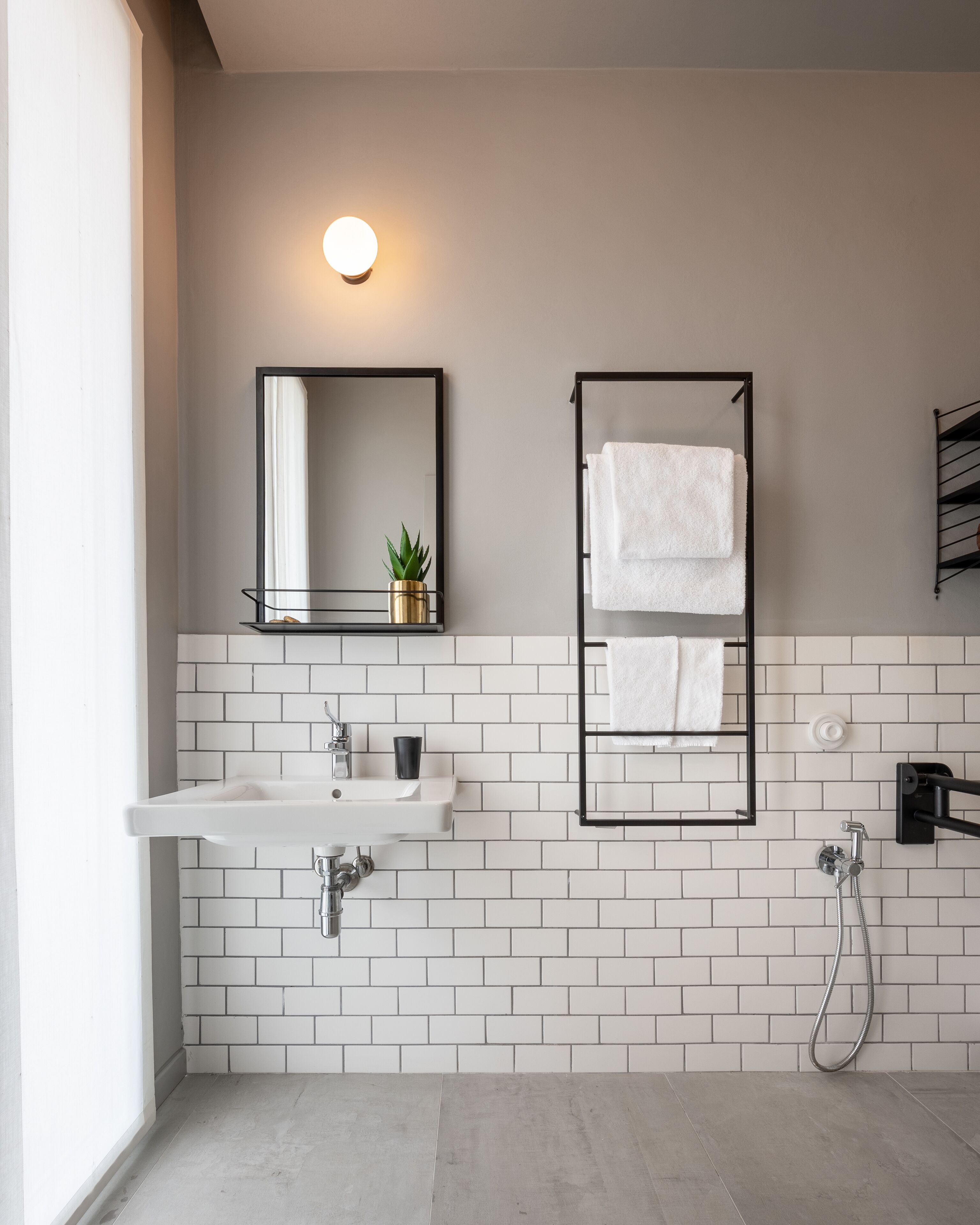 Uma casa de banho moderna com uma pia branca, um espelho, um porta-toalhas e um chuveiro.