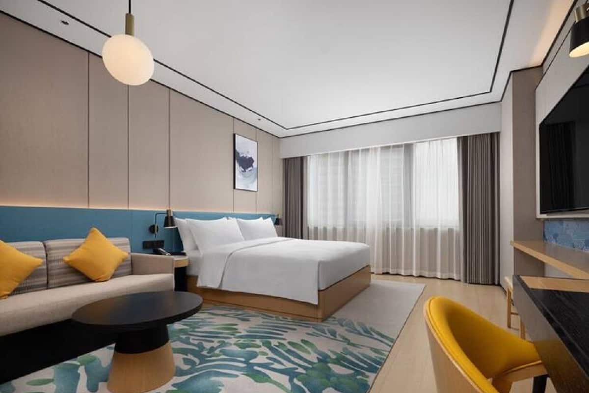 Quarto de hotel moderno com cama, sofá e área de refeições.