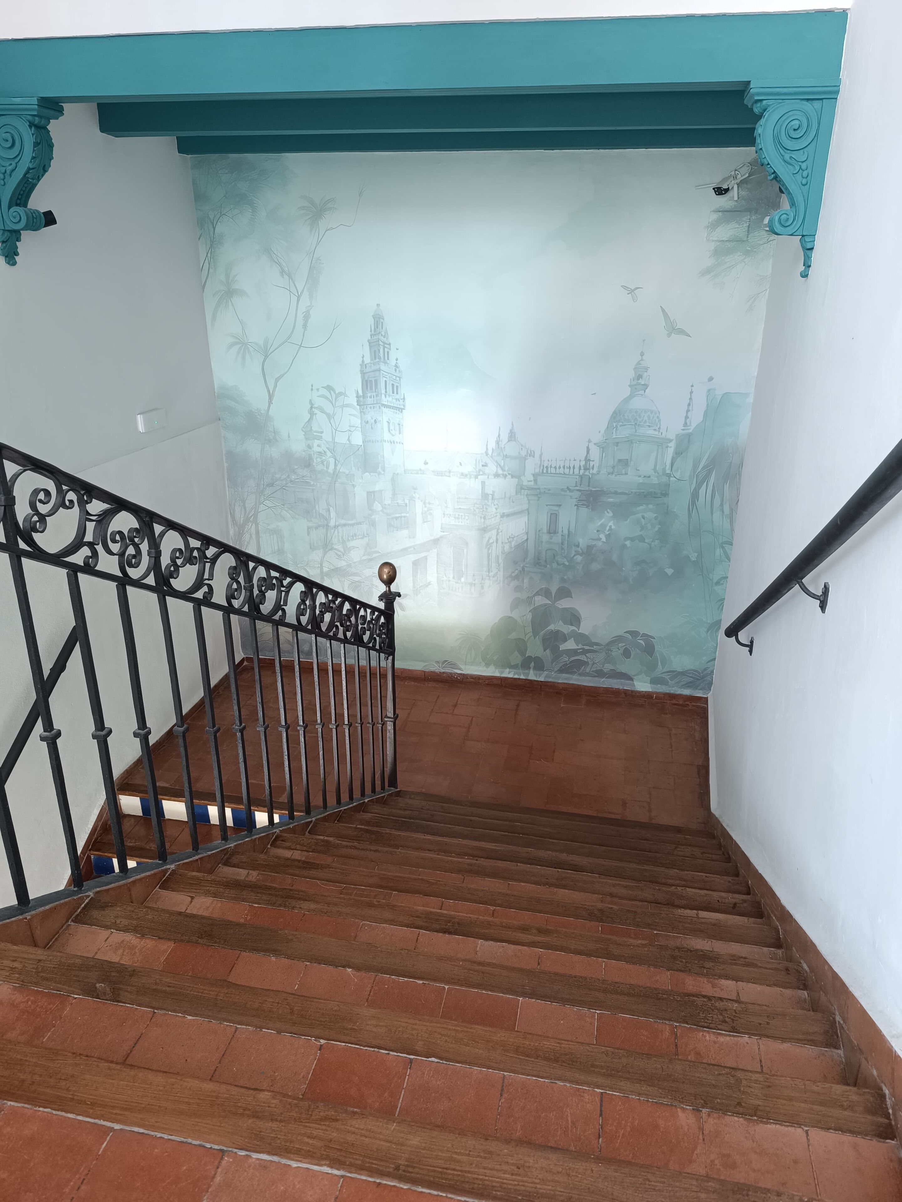 Uma escadaria com um mural de uma paisagem urbana histórica.