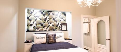 Quarto com cama, um candelabro, uma porta e parede com padrão floral.