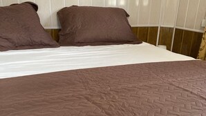 Uma cama com um edredom castanho e duas almofadas.
