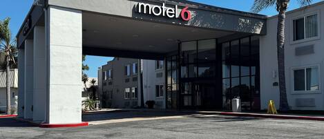 Um motel com design moderno, destacando uma grande cobertura de entrada e uma visão clara da área de estacionamento.