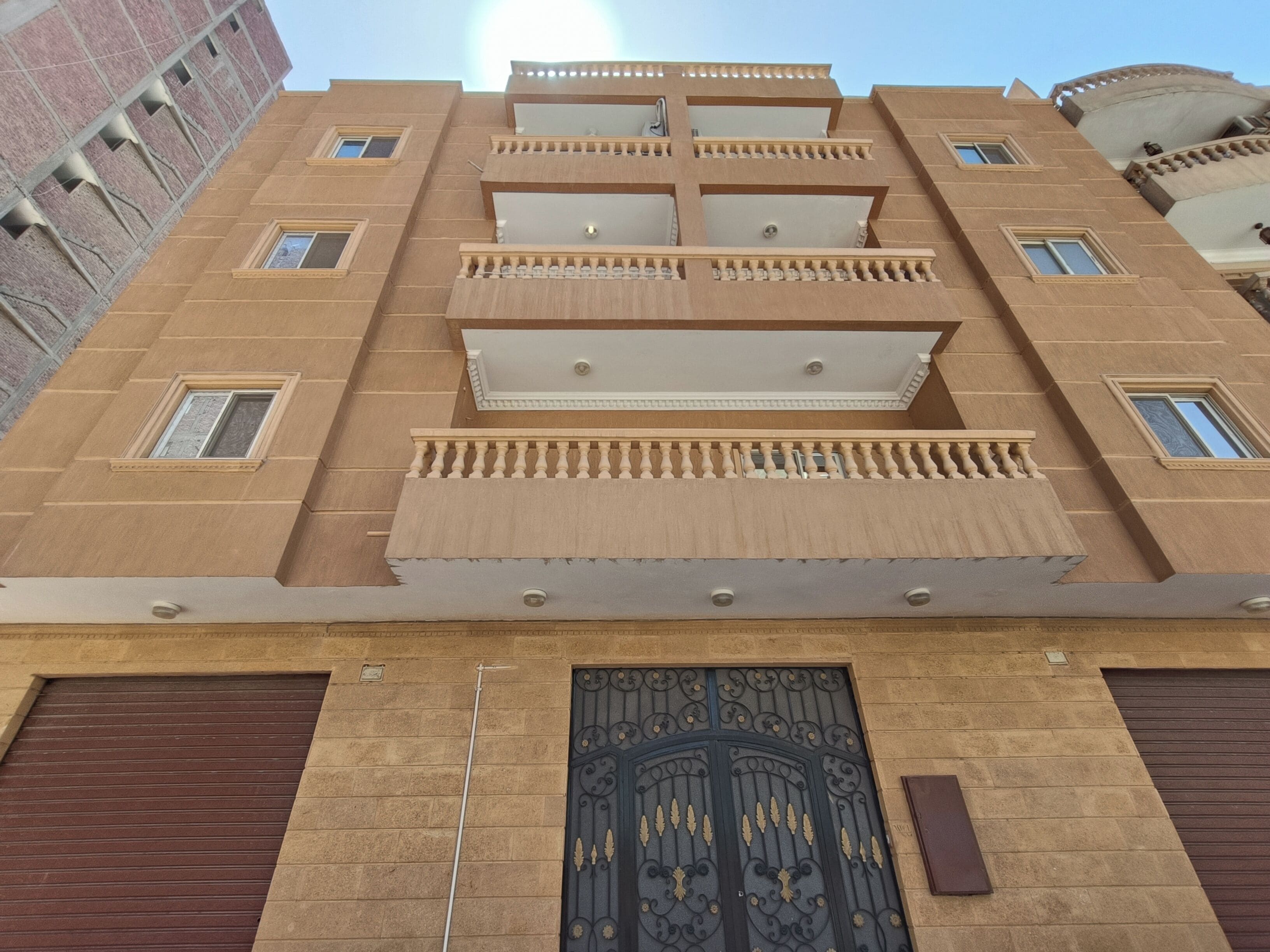 Um edifício de vários andares com varandas, janelas amplas e um portão de entrada decorativo.