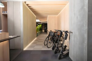 Um corredor moderno com paredes de madeira, piso quadriculado e bicicletas encostadas na parede.