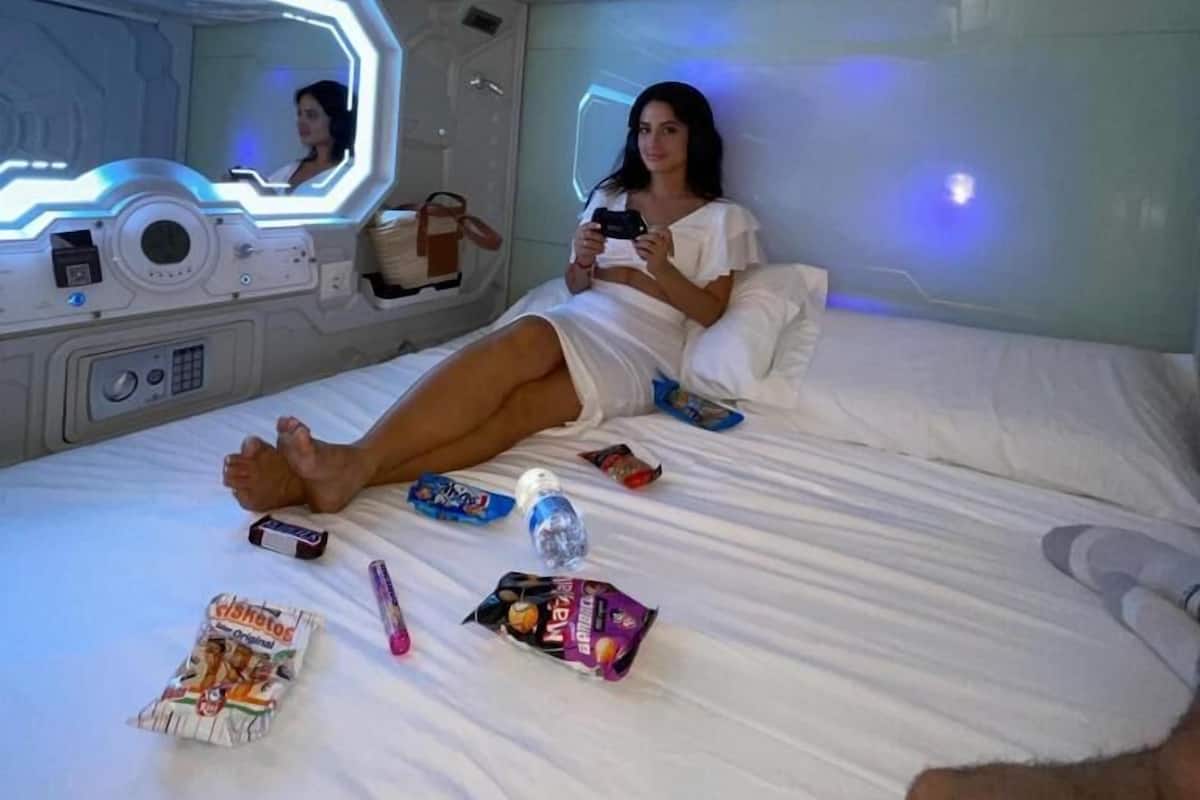 Um quarto futurista com uma cama, um painel de controle e uma janela.