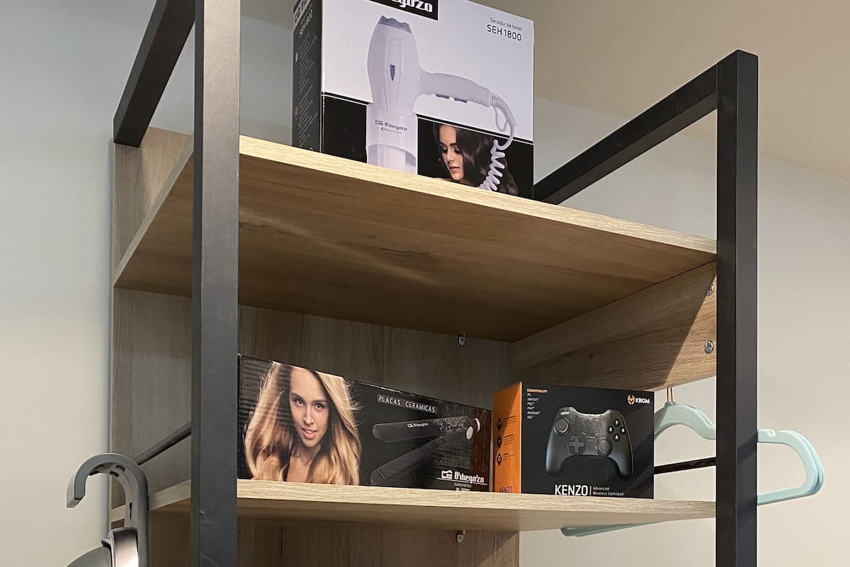 Uma cama beliche com cabeceira, um secador de cabelo e uma caixa de escovas de cabelo de cerâmica na prateleira superior.
