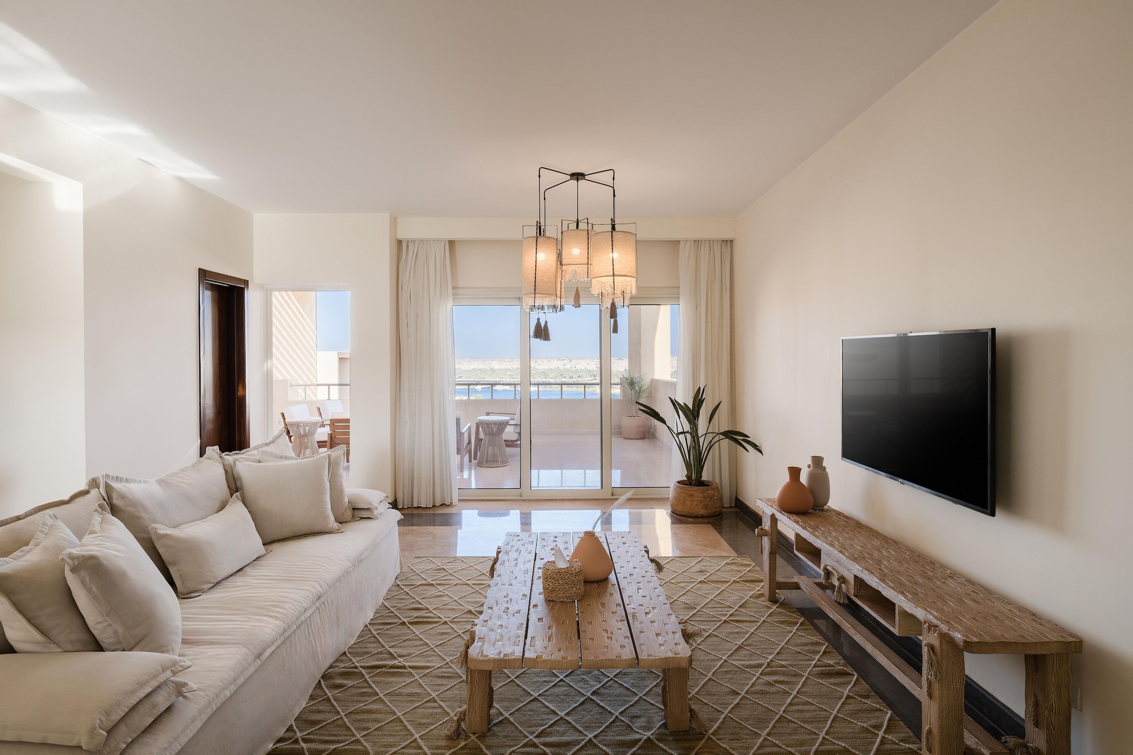 Uma sala de estar ampla com sofá, mesa de centro, TV e varanda com vista.