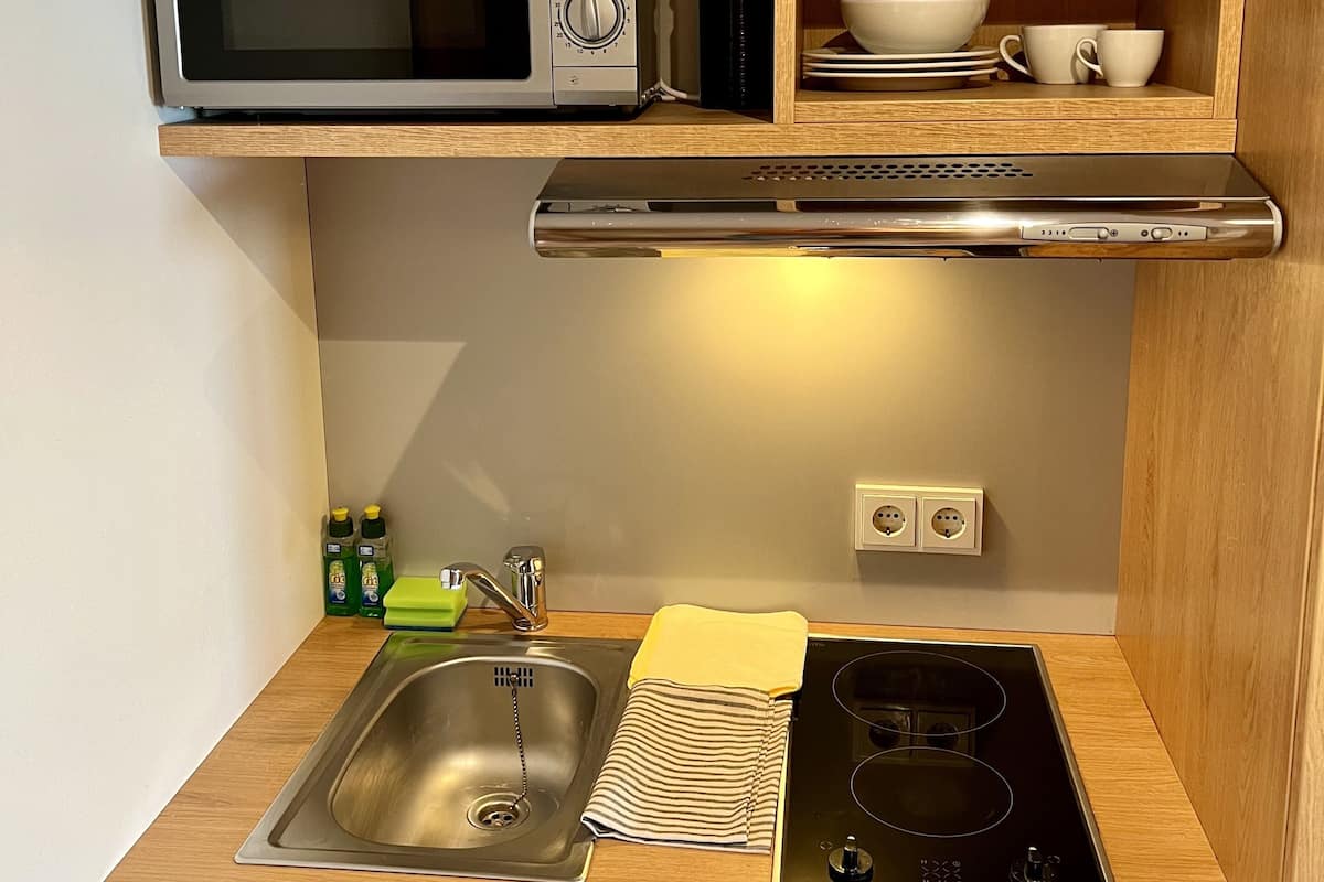 Uma cozinha compacta com micro-ondas, chaleira e fogão pequeno.