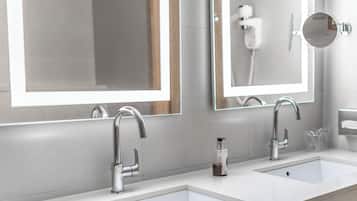 Uma casa de banho moderna com duas pias, um espelho e um chuveiro manual.
