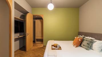 Quarto com uma cama, um guarda-roupa de madeira, uma televisão e um candeeiro.