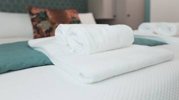 Cama bem arrumada com lençóis brancos e almofada verde-água.