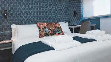 Quarto de hotel com uma cama grande, uma escrivaninha e uma janela.