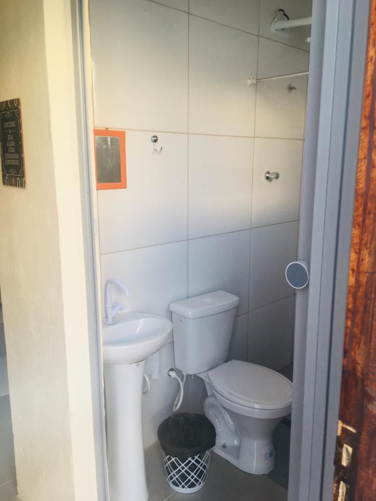 Casa de banho com sanita, lavatório e um contentor de lixo.