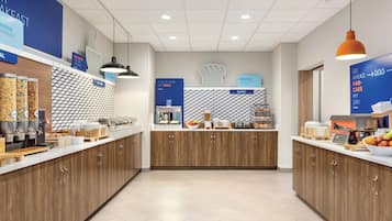 Uma área de café da manhã moderna com balcão, máquinas de café e uma seção de padaria.