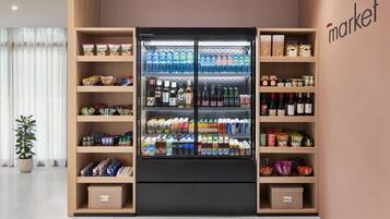 Um expositor refrigerado com diversas bebidas e lanches, rodeado por prateleiras com produtos embalados.