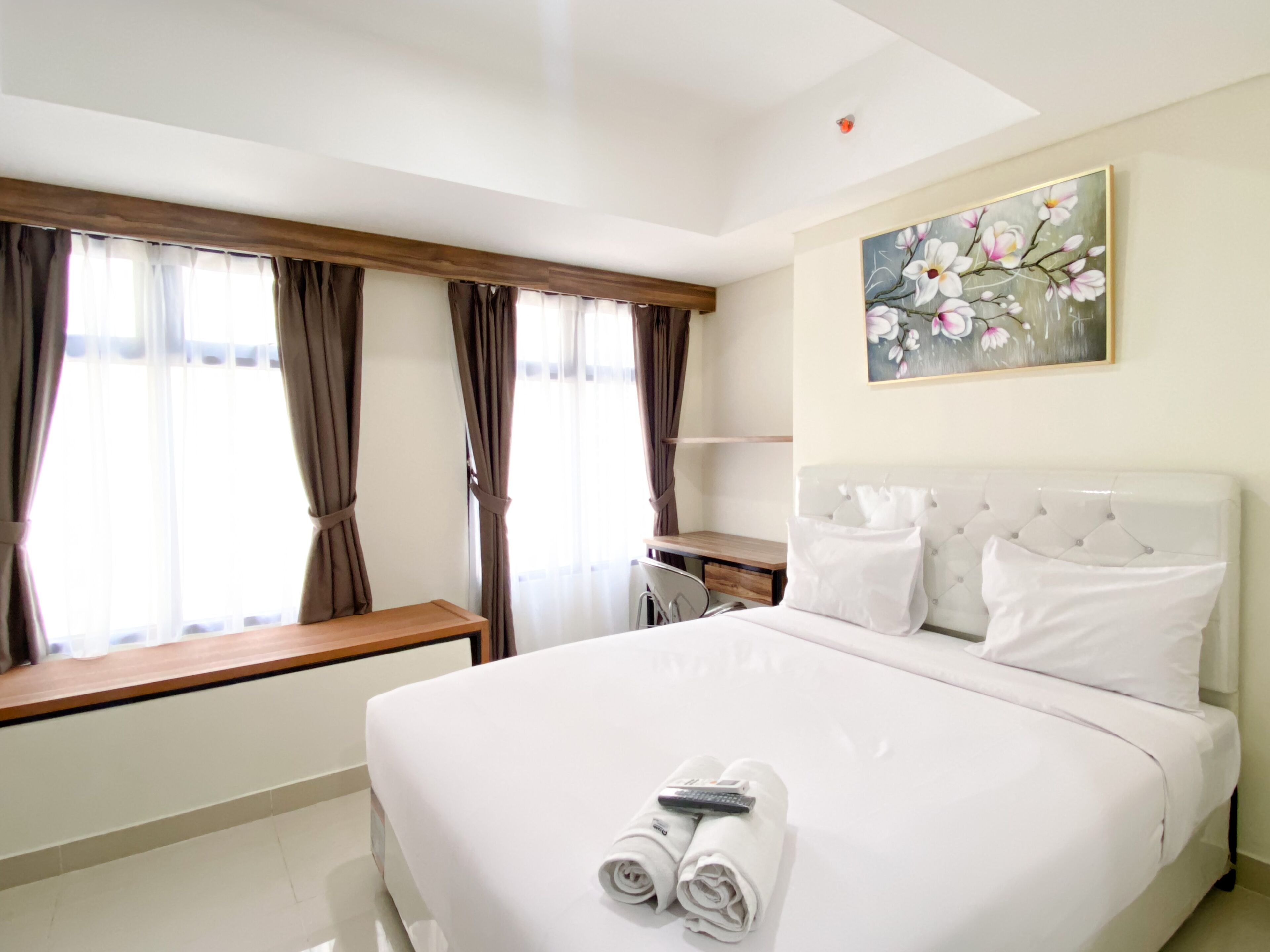 Quarto de hotel com uma cama grande, uma escrivaninha e um quadro na parede.