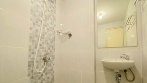 Casa de banho com chuveiro, lavatório e espelho.