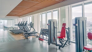 Academia moderna com equipamentos de exercício, janelas amplas e teto de madeira.