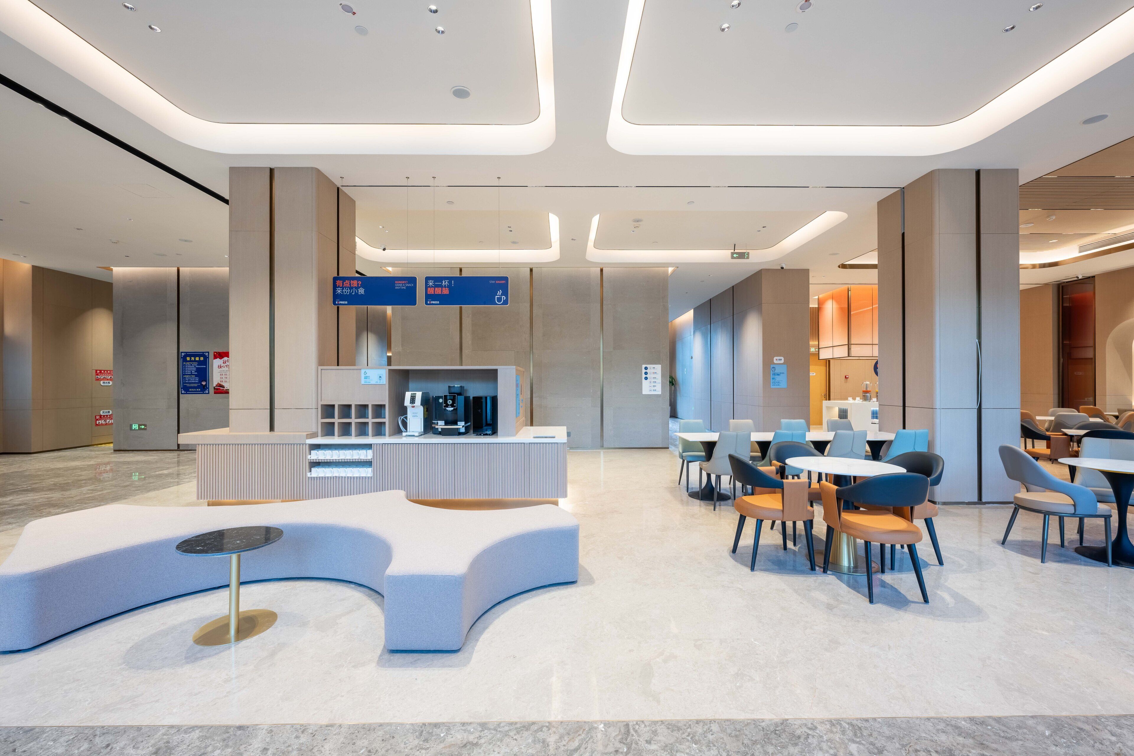 Um lobby moderno com balcão de recepção, área de estar e placas de sinalização.
