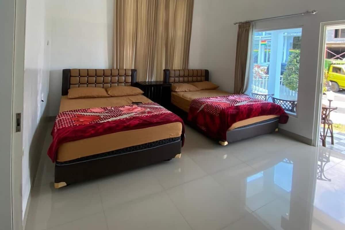 Quarto de hotel com duas camas, uma janela grande e vista para o exterior.