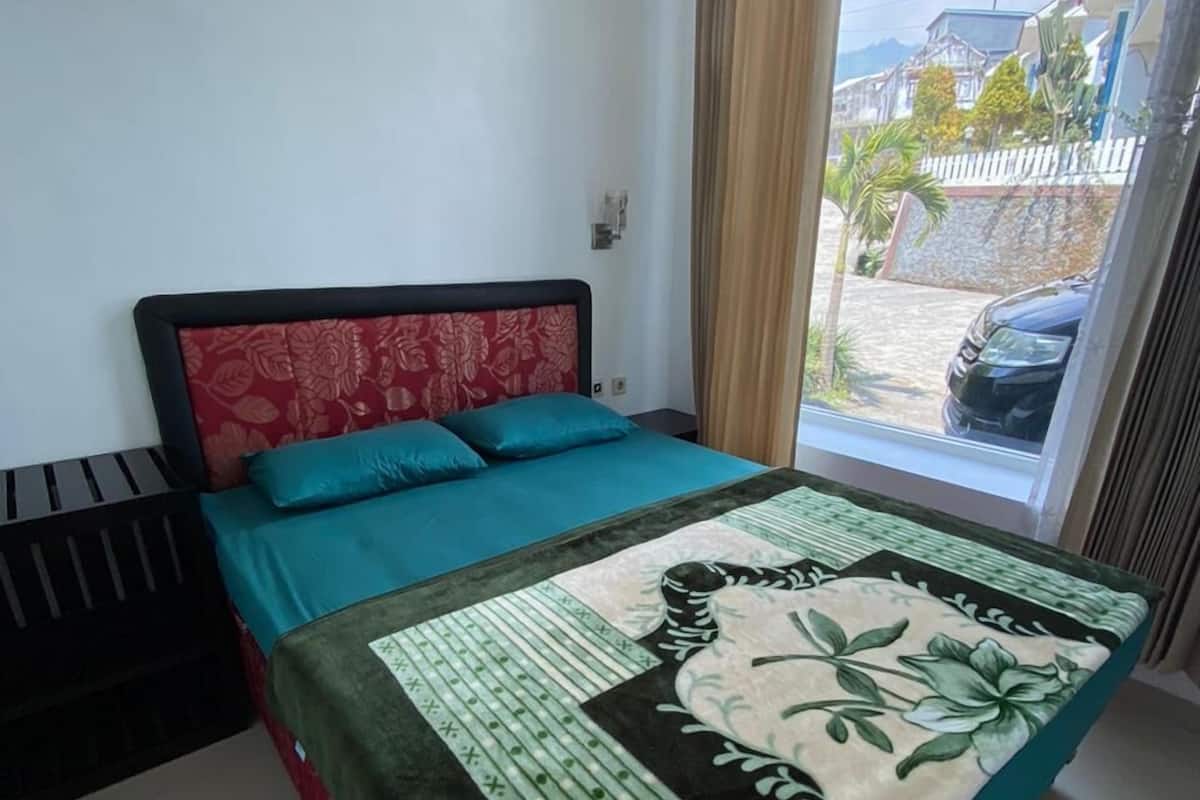 Quarto com cama, janela com cortinas e vista para o exterior.