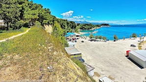 Vista aérea de uma área costeira com um estacionamento, um pequeno edifício e uma praia.
