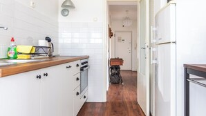 Cozinha com armários brancos, bancada de madeira e geladeira de aço inoxidável.