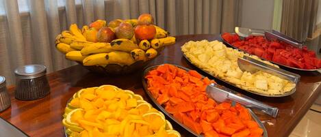 Uma mesa de buffet com diversas frutas e legumes.