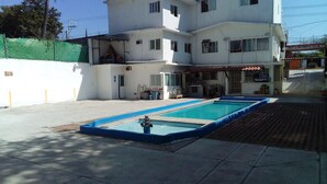 Um edifício de dois andares com uma piscina em primeiro plano.
