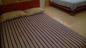 Quarto com duas camas, cada uma com colcha listrada.