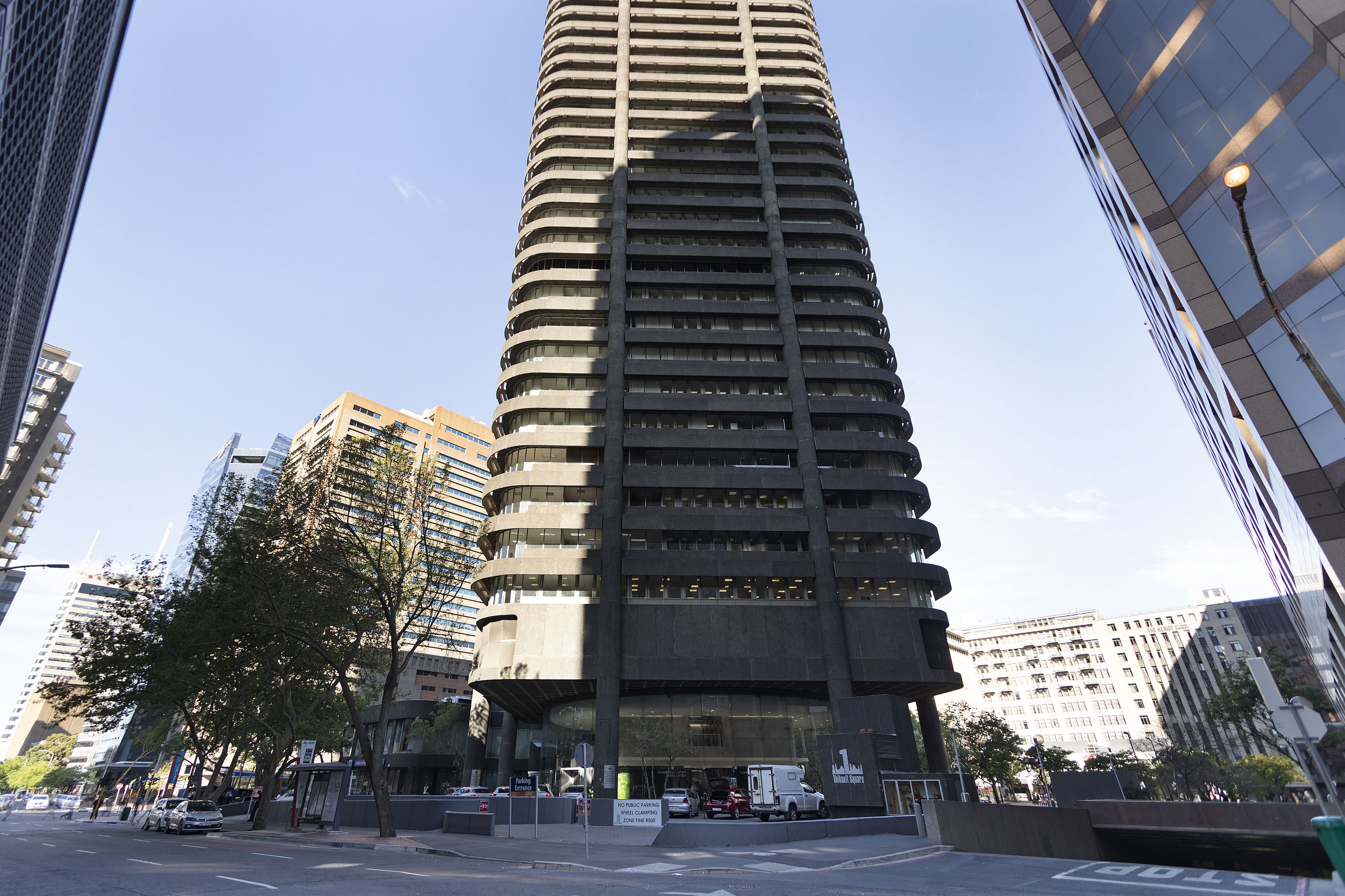 Um edifício alto e cilíndrico com fachada curva e vários andares.